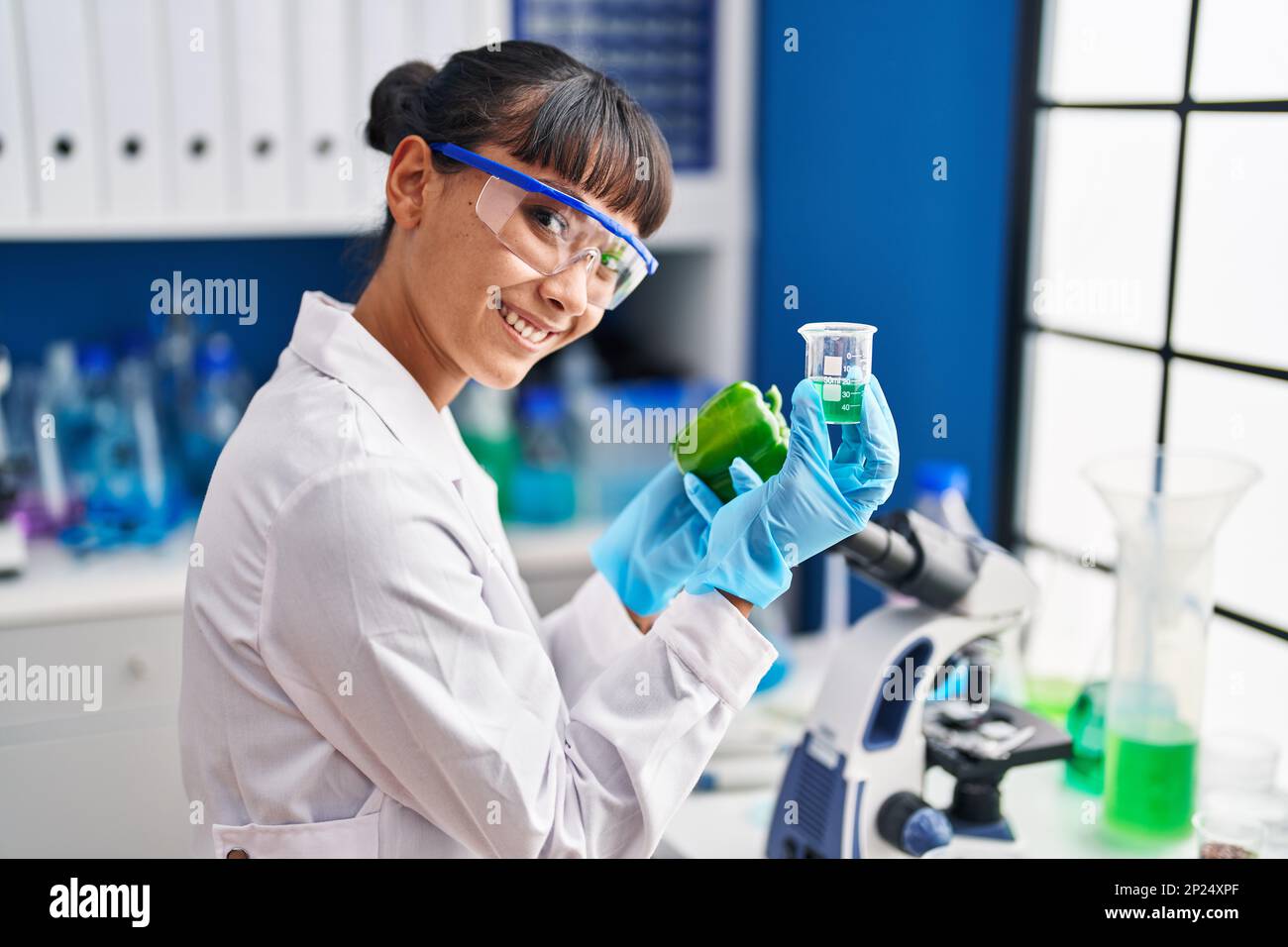 Young beautiful hispanic woman scientist holding pepper measuring ...