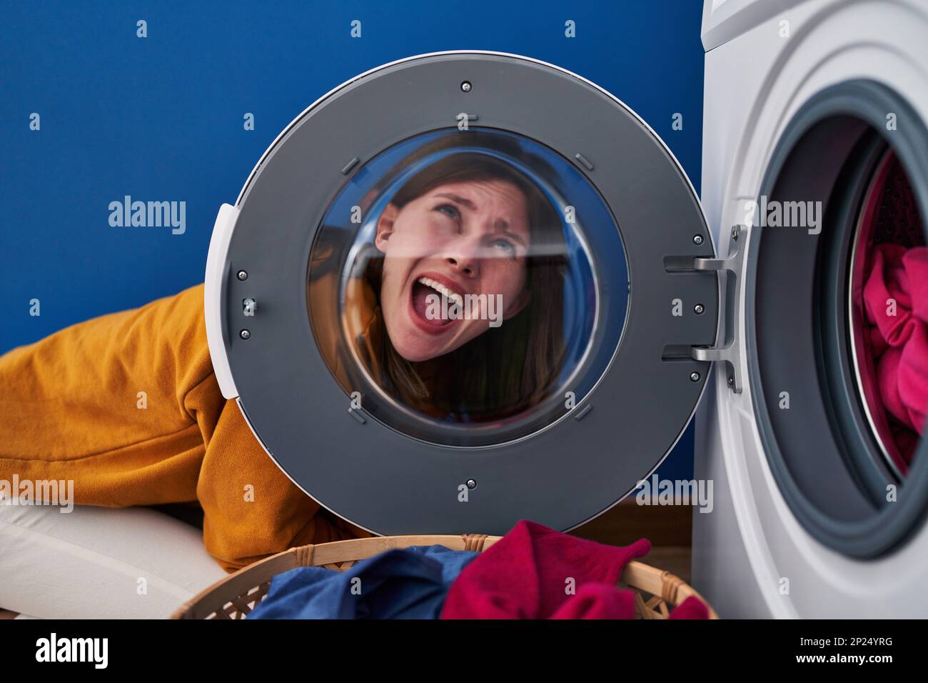 Young brunette woman looking through the washing machine window angry ...