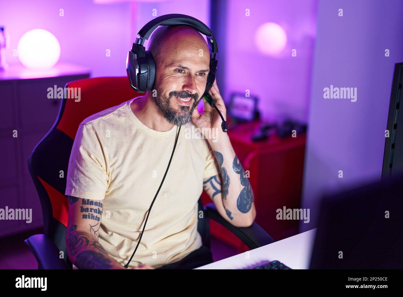 Young bald man streamer playing video game using computer at gaming ...