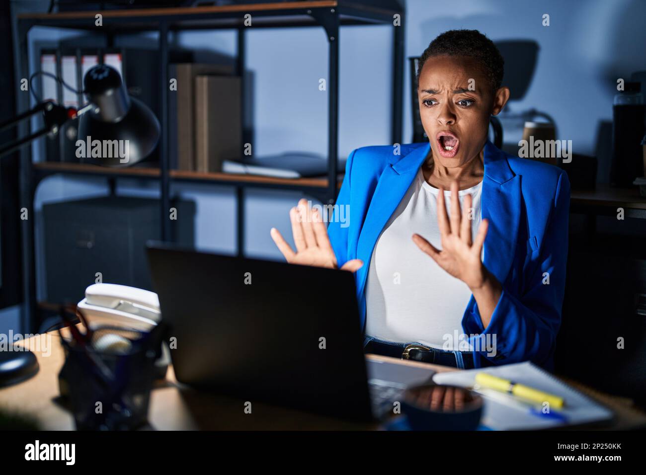 Beautiful african american woman working at the office at night afraid ...