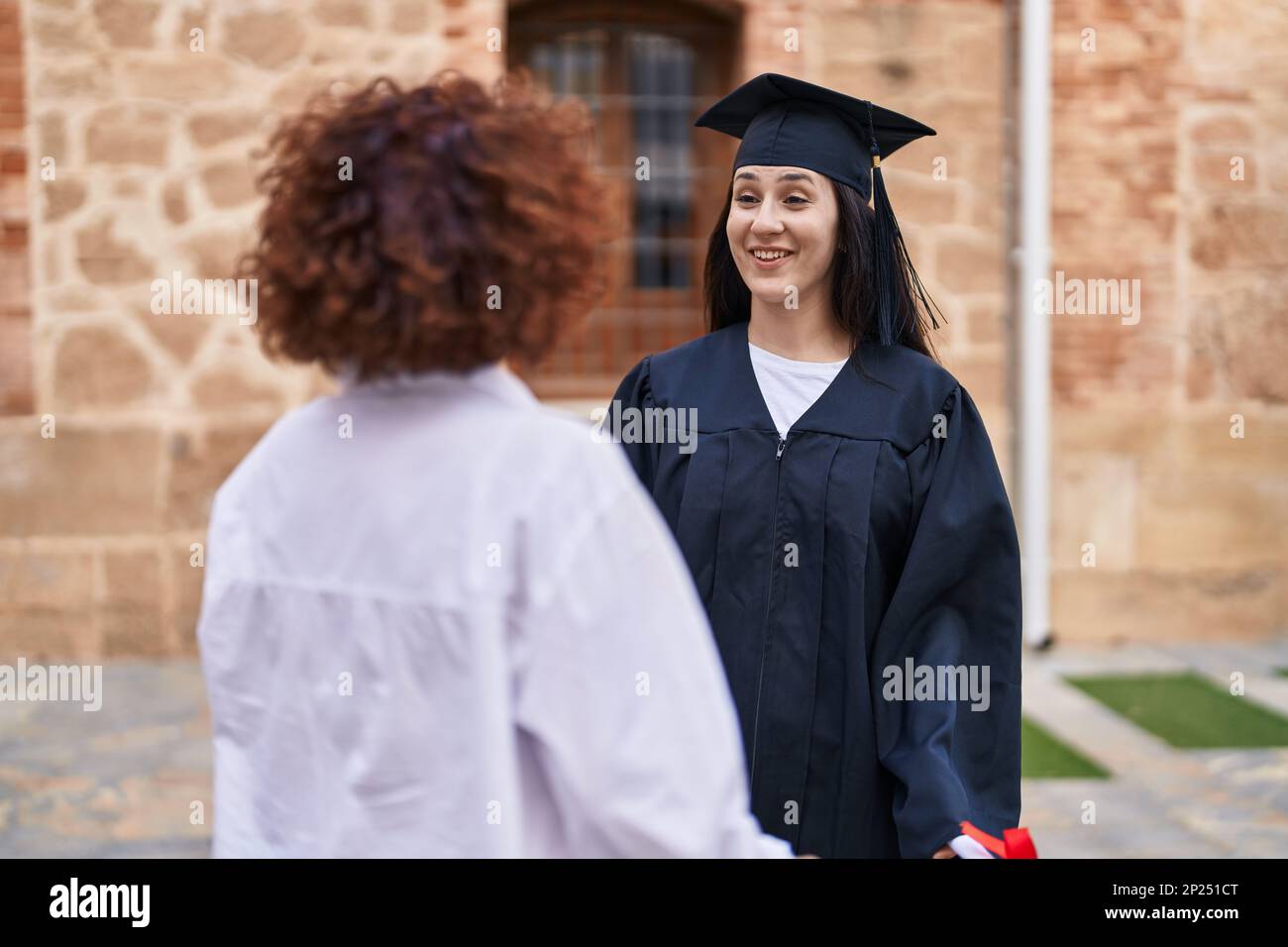 Two women mother and daughter celebrating graduation at campus ...