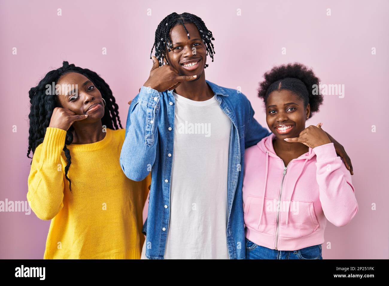 Group of three young black people standing together over pink ...