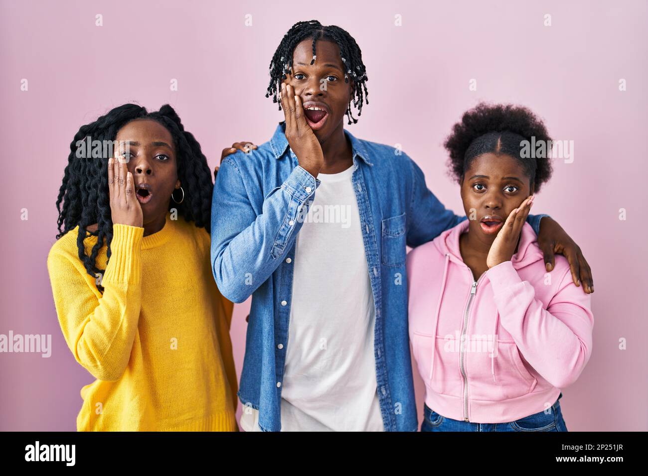 Group of three young black people standing together over pink ...
