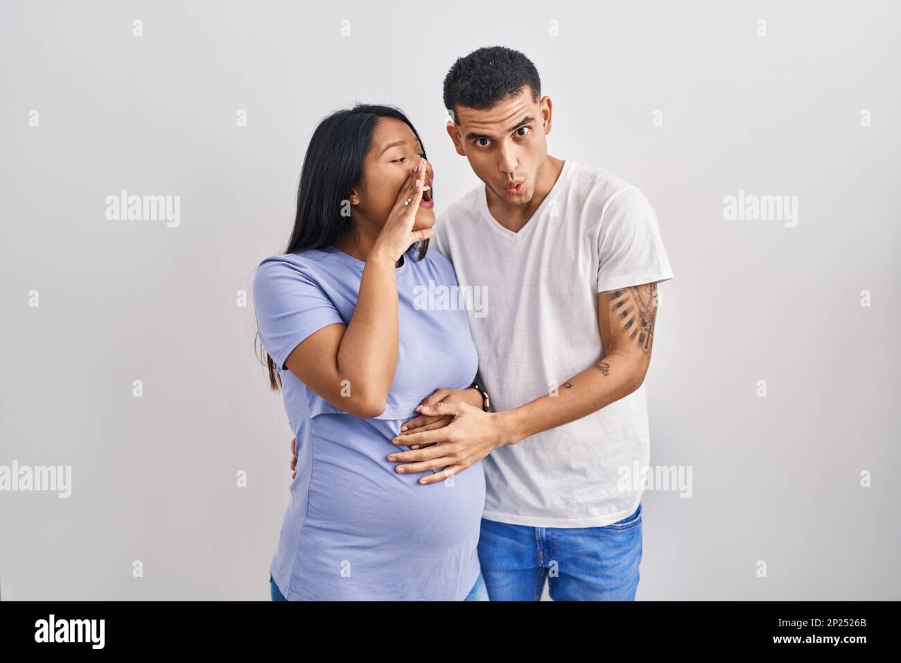 Young hispanic couple expecting a baby standing over background hand on ...