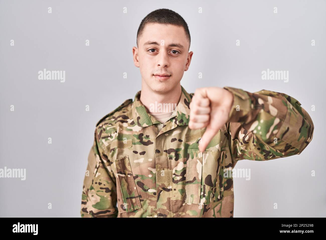 Young man wearing camouflage army uniform looking unhappy and angry ...