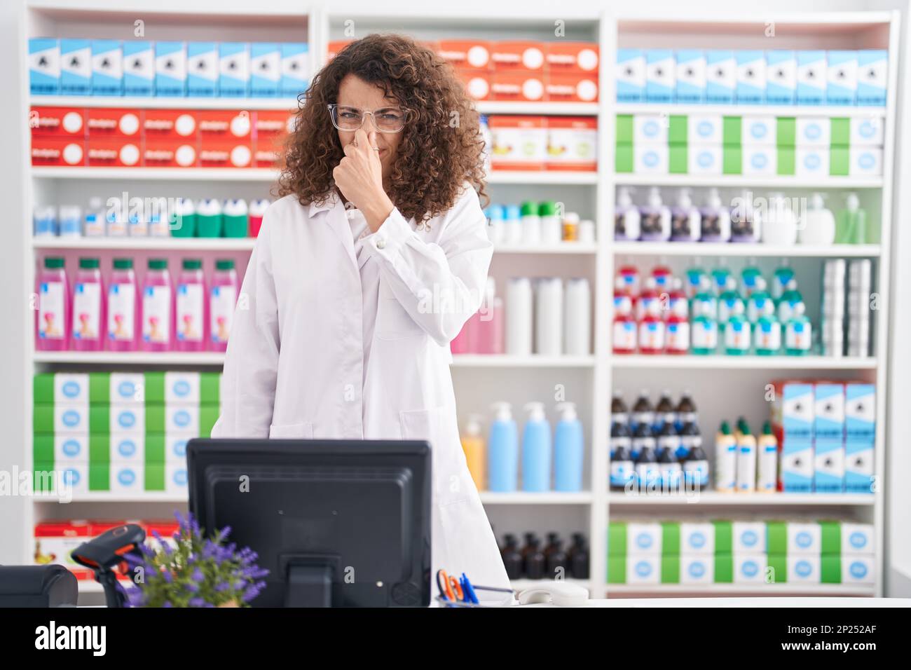 Hispanic woman with curly hair working at pharmacy drugstore smelling ...