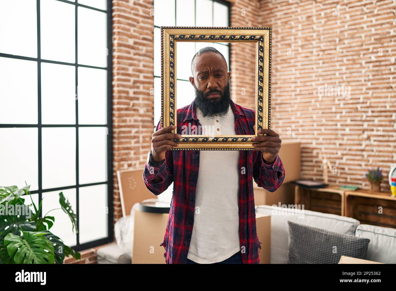 African american man putting face in empty frame skeptic and nervous ...