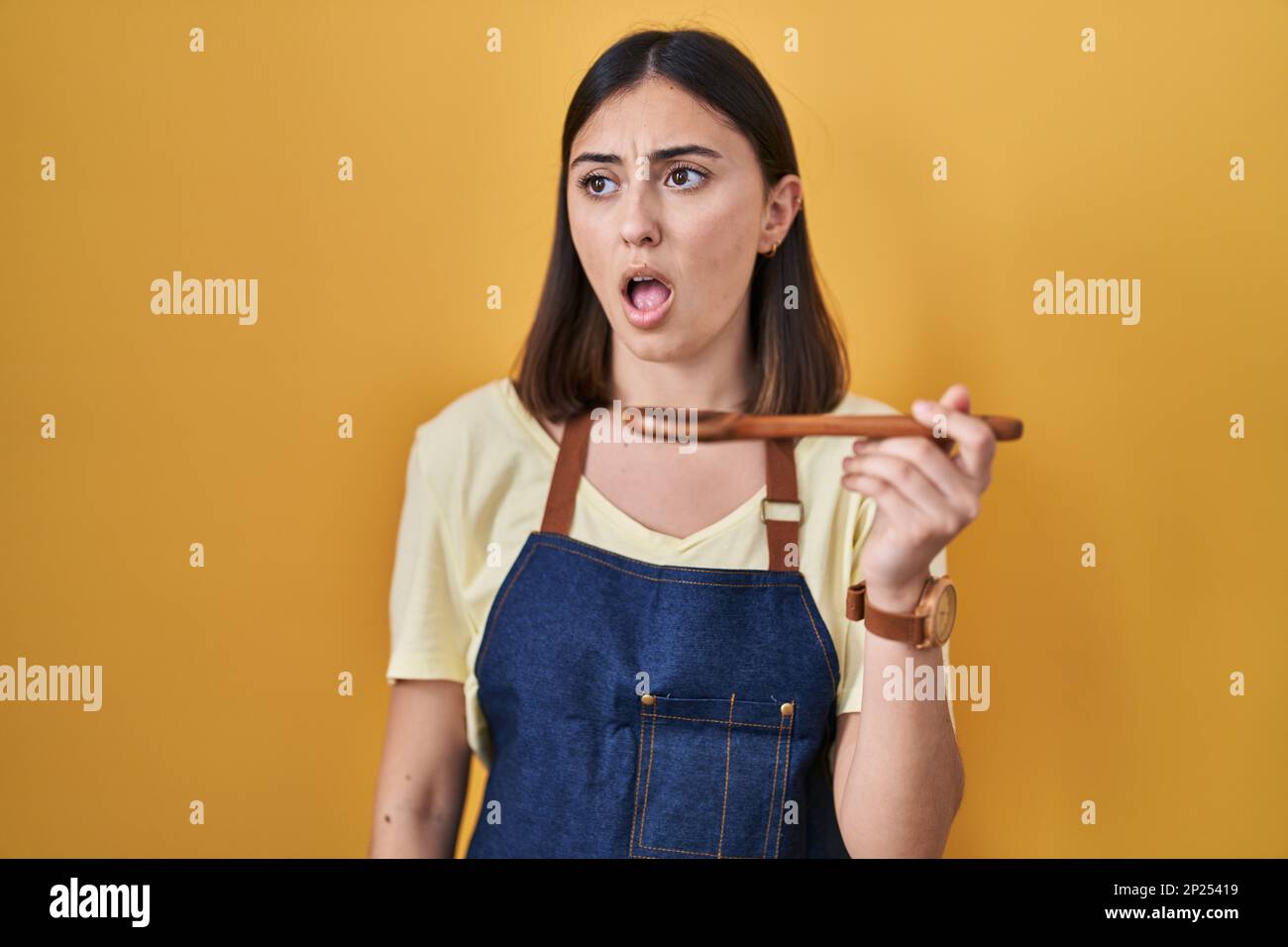 Hispanic girl eating healthy wooden spoon angry and mad screaming ...