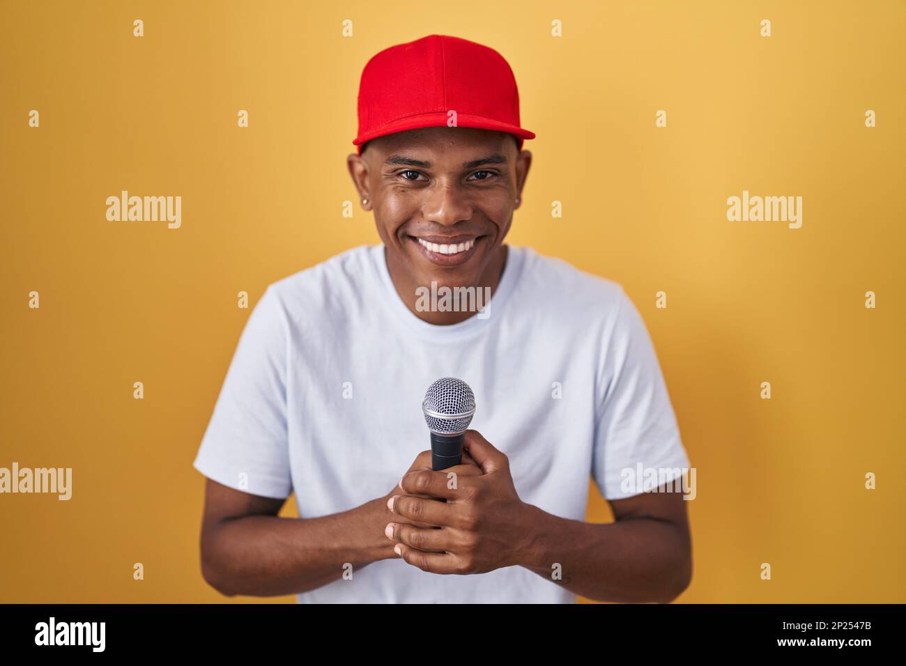 Young hispanic man singing song using microphone smiling and laughing ...