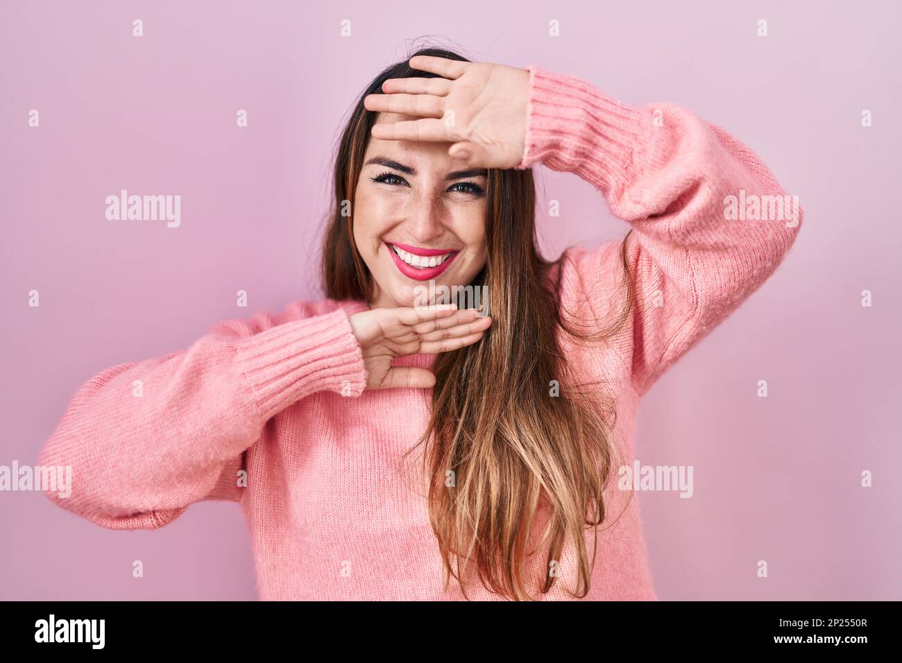 Young hispanic woman standing over pink background smiling cheerful ...