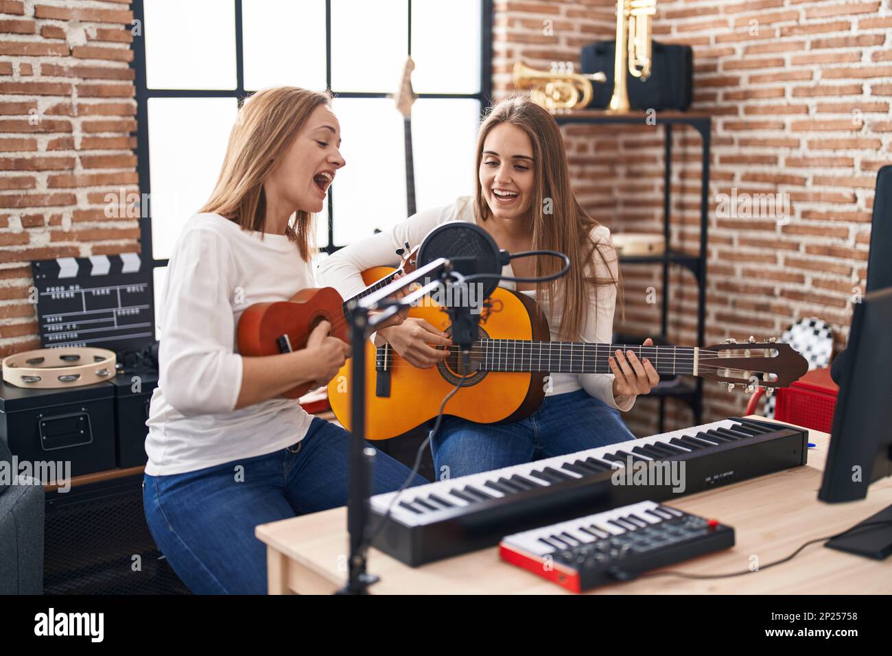 Two women musicians singing song playing classical guitar and ukulele ...