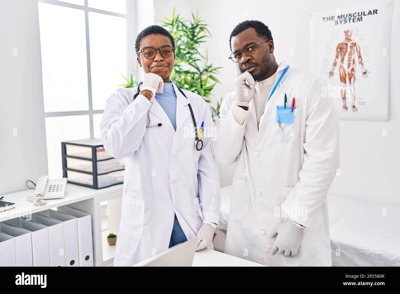 Young african american doctors working at medical clinic serious face ...