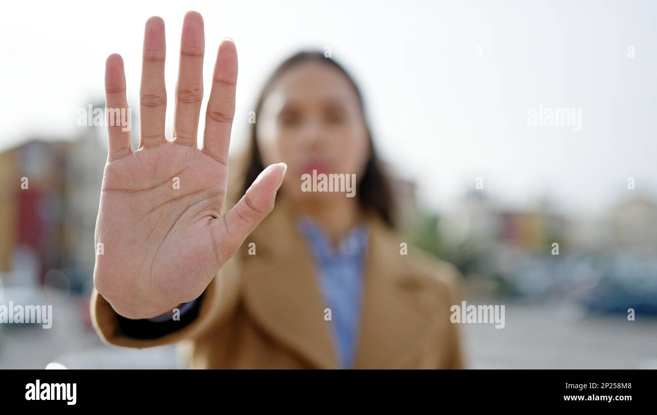 Young beautiful hispanic woman doing stop gesture with hand at street ...