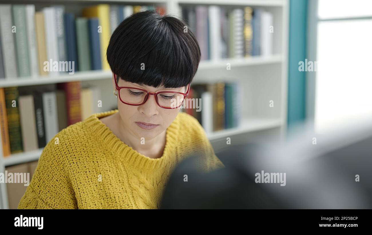 Young chinese woman student using computer studying at library ...