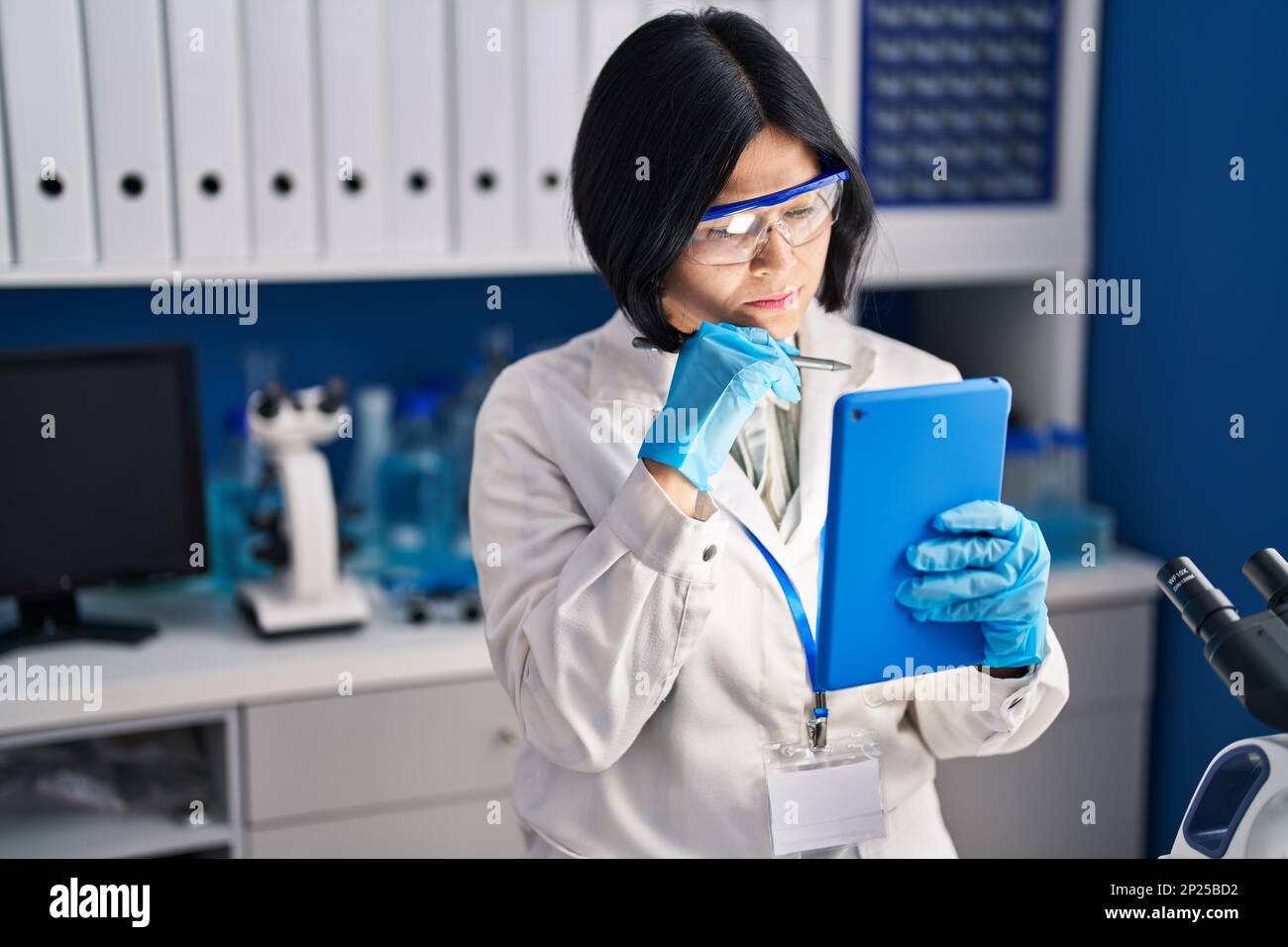 Young chinese woman scientist using touchpad working at laboratory ...