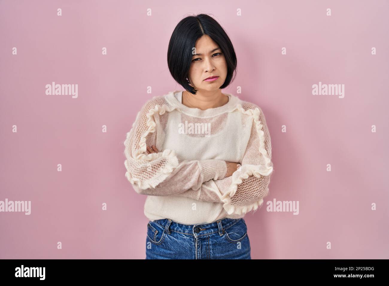 Young asian woman standing over pink background skeptic and nervous ...