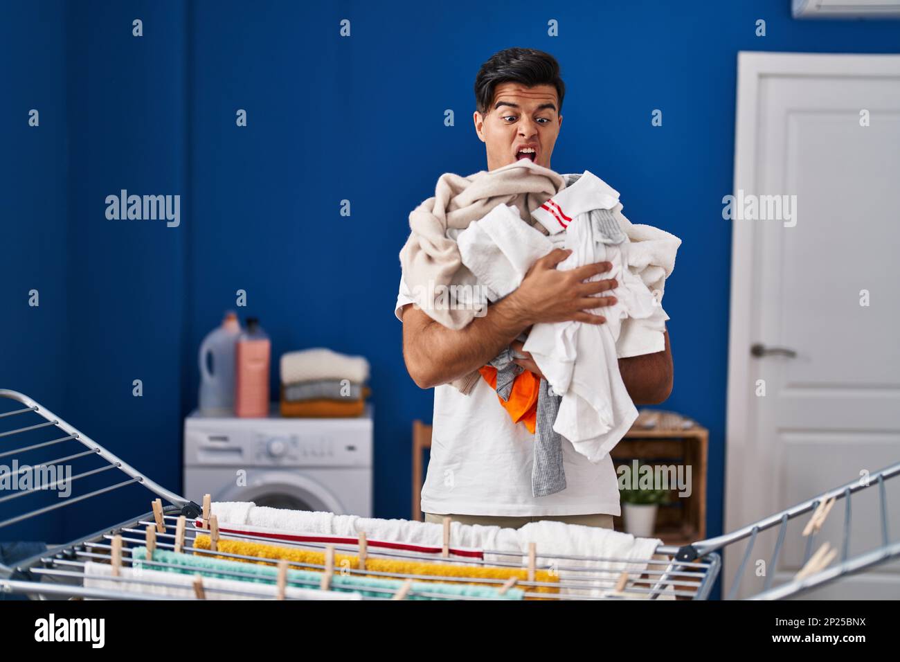 Hispanic man hanging clothes at clothesline angry and mad screaming ...