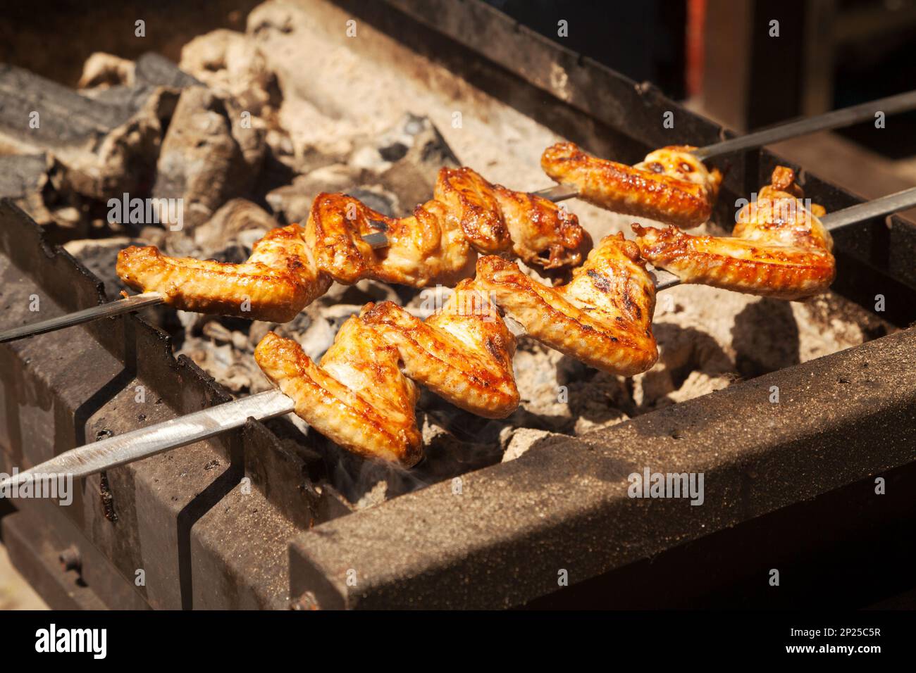 Barbecue chicken wings on skewers being roasted. Cooking food on coals ...