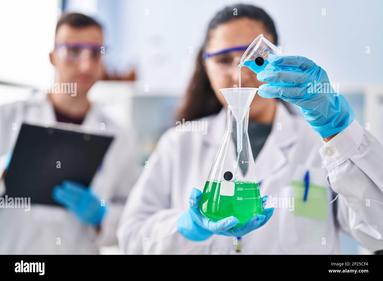 Man and woman wearing scientist uniform write on document measuring ...
