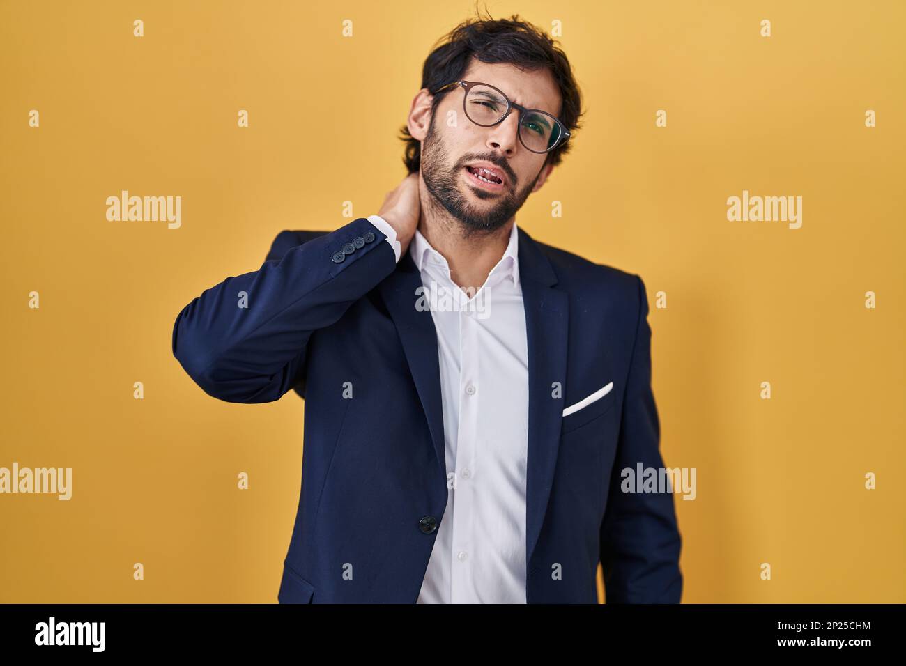 Handsome latin man standing over yellow background suffering of neck ...