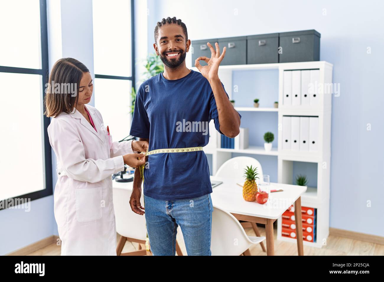 Dietitian at the clinic using tape measure measuring waist of client ...