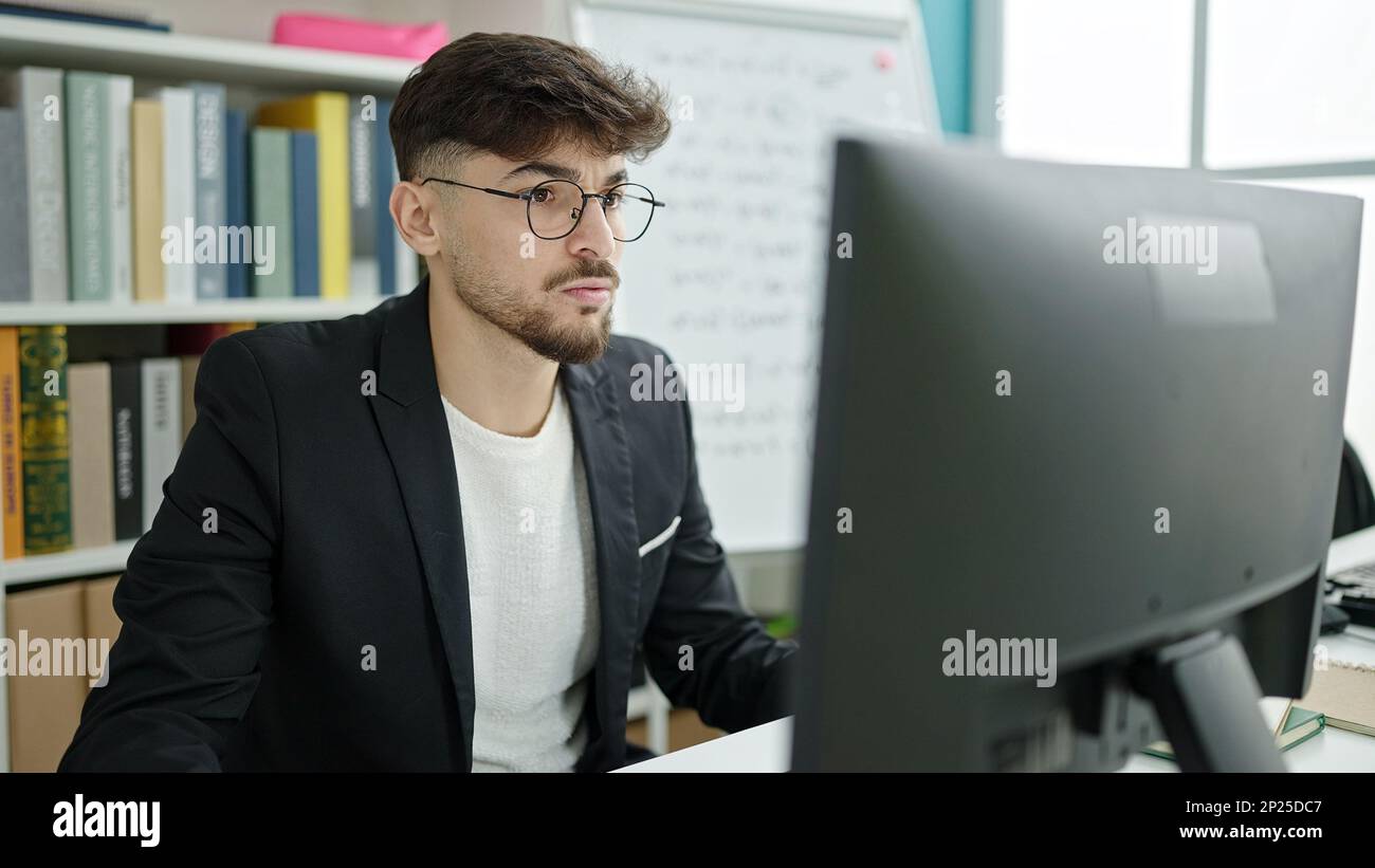 Young arab man student using computer studying at university classroom ...