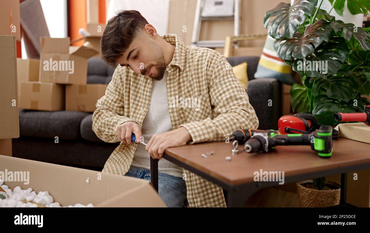 Young arab man repairing table using screwdriver at new home Stock ...