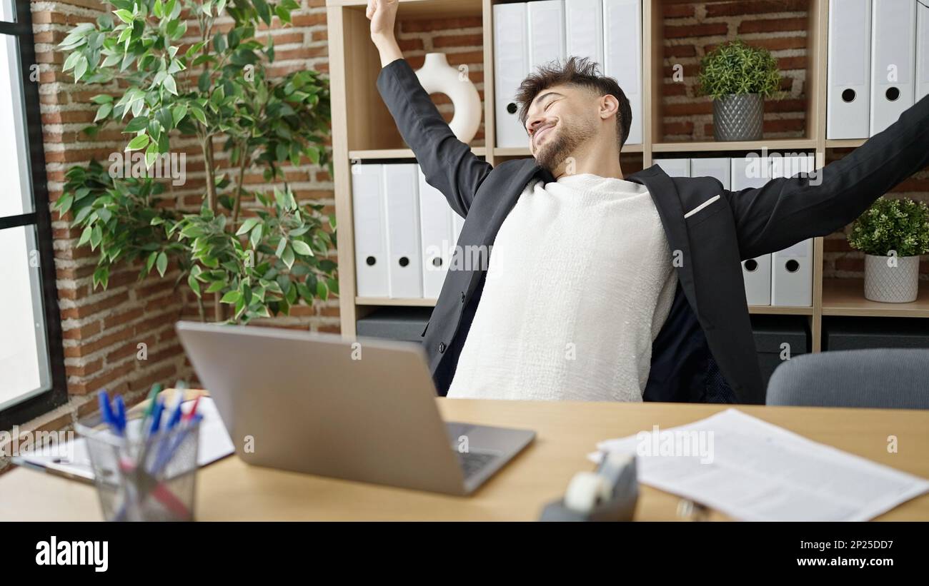 Young arab man business worker using laptop stretching arms at office ...