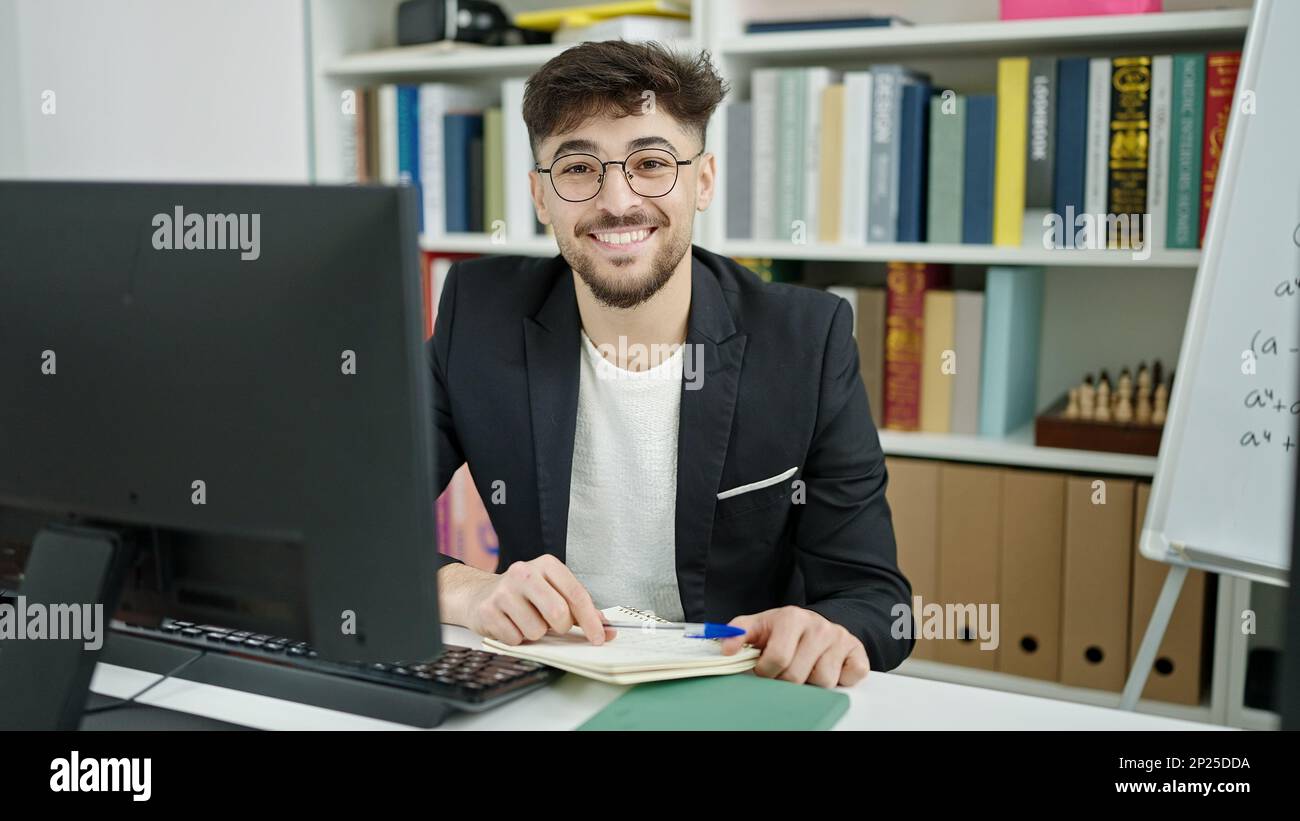 Young arab man student using computer writing on notebook at university ...