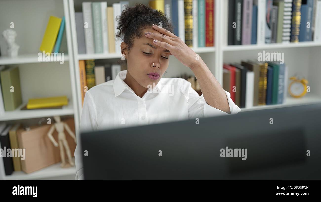 African american woman student using computer stressed at library ...