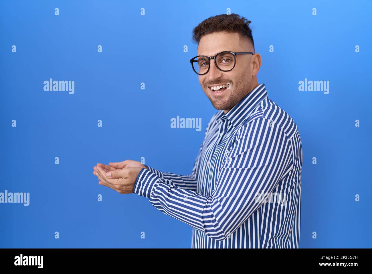 Hispanic man with beard wearing glasses pointing aside with hands open ...