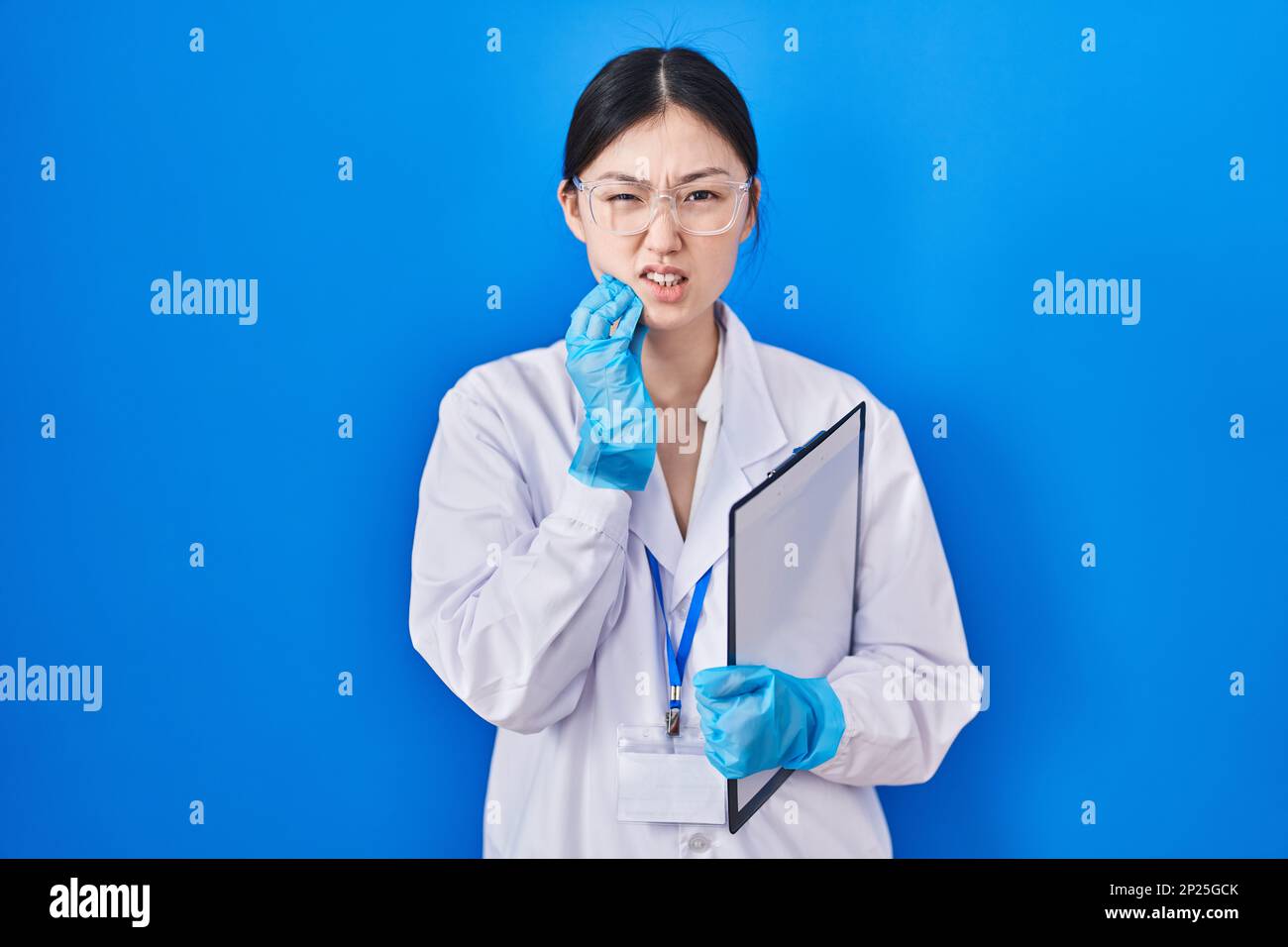 Chinese young woman working at scientist laboratory touching mouth with ...