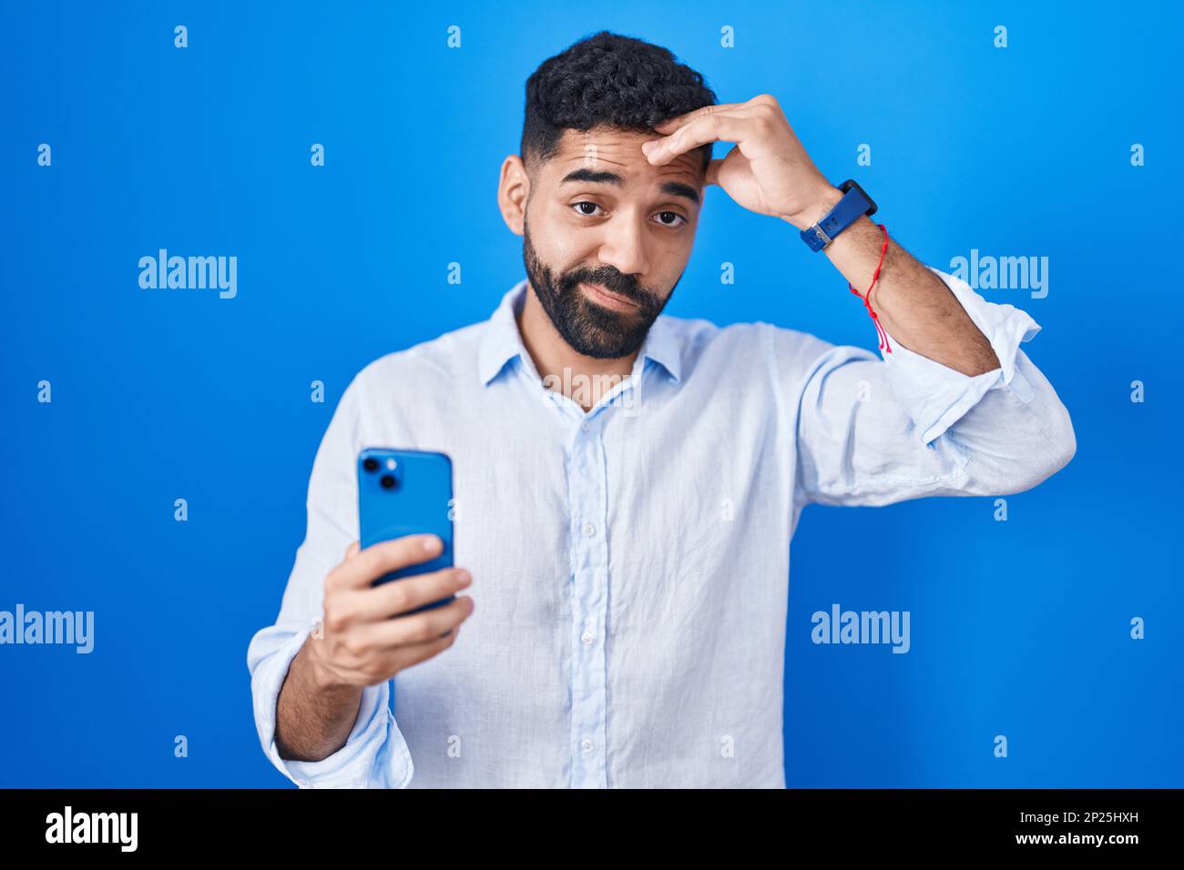 Hispanic Man With Beard Using Smartphone Typing Message Worried And