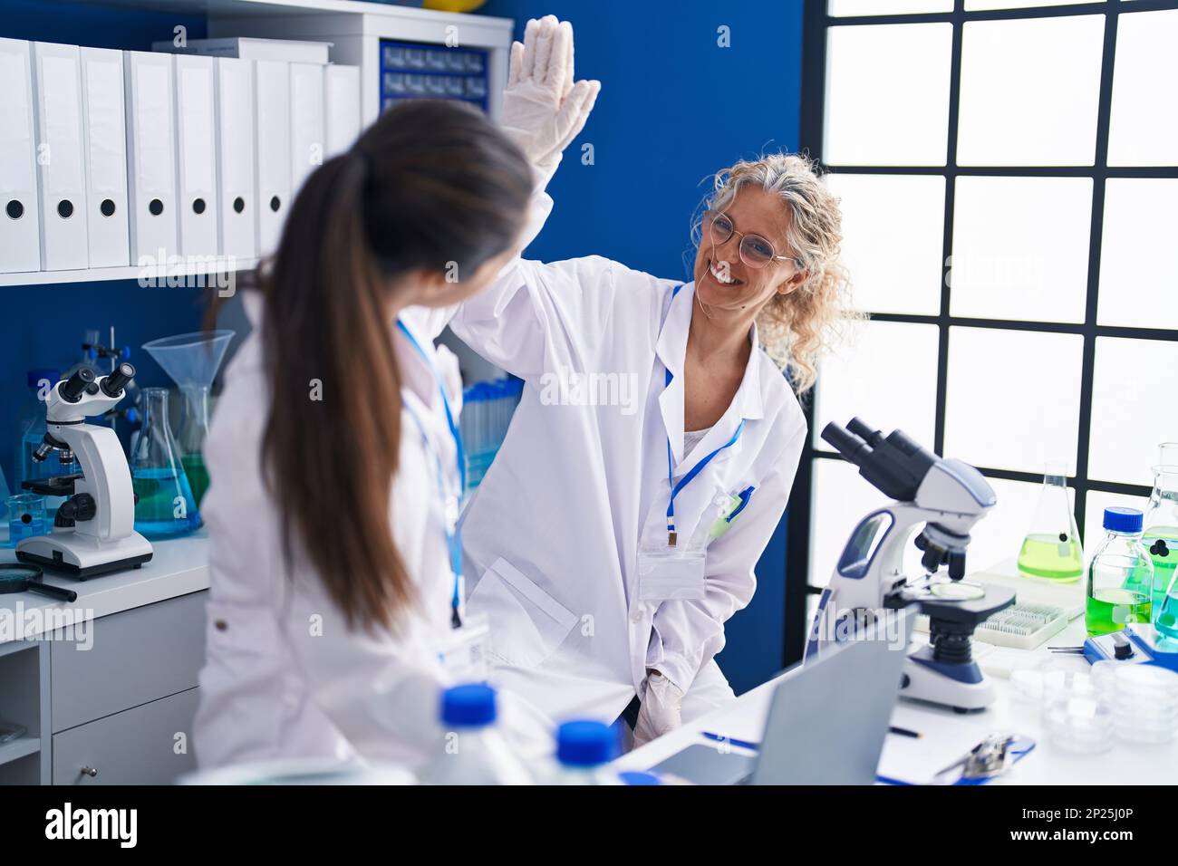 Two women scientists high five with hands raised up working at ...