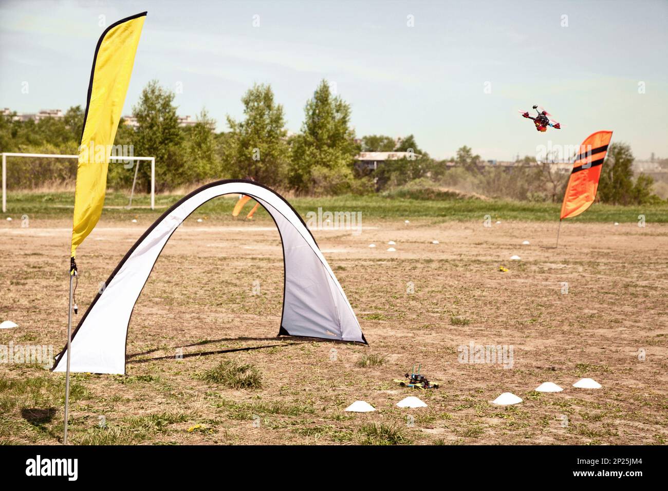 Drone racing in a field with gates and flags. Two copters flying and ...