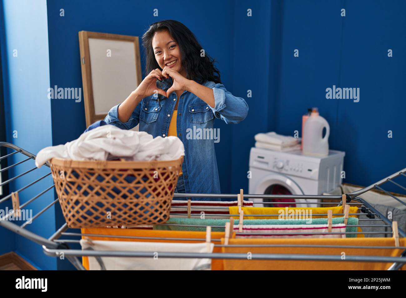 Young asian woman hanging clothes at clothesline smiling in love doing ...