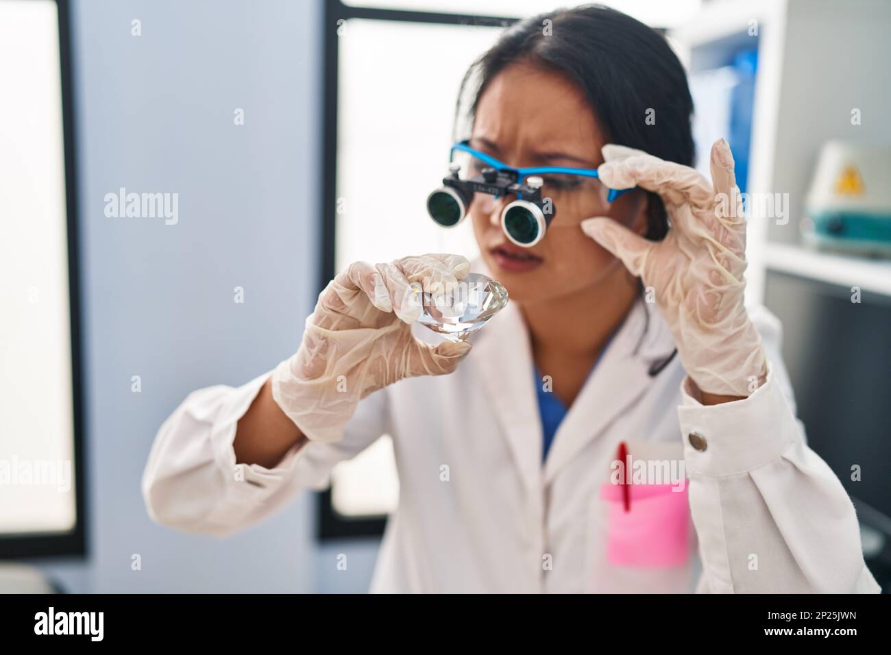 Young chinese woman wearing scientist uniform examining diamond at ...