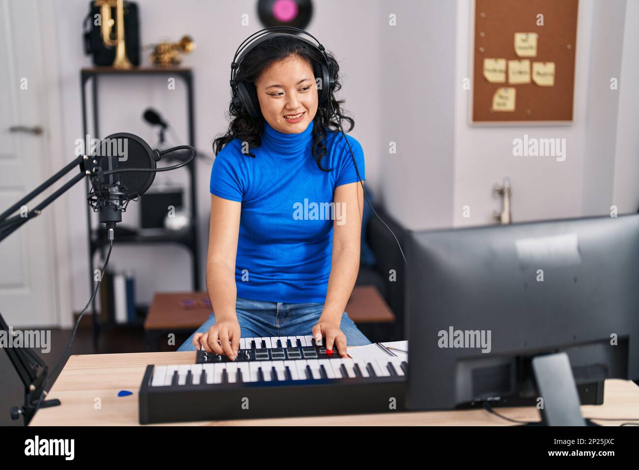 Young chinese woman musician playing piano keyboard at music studio ...