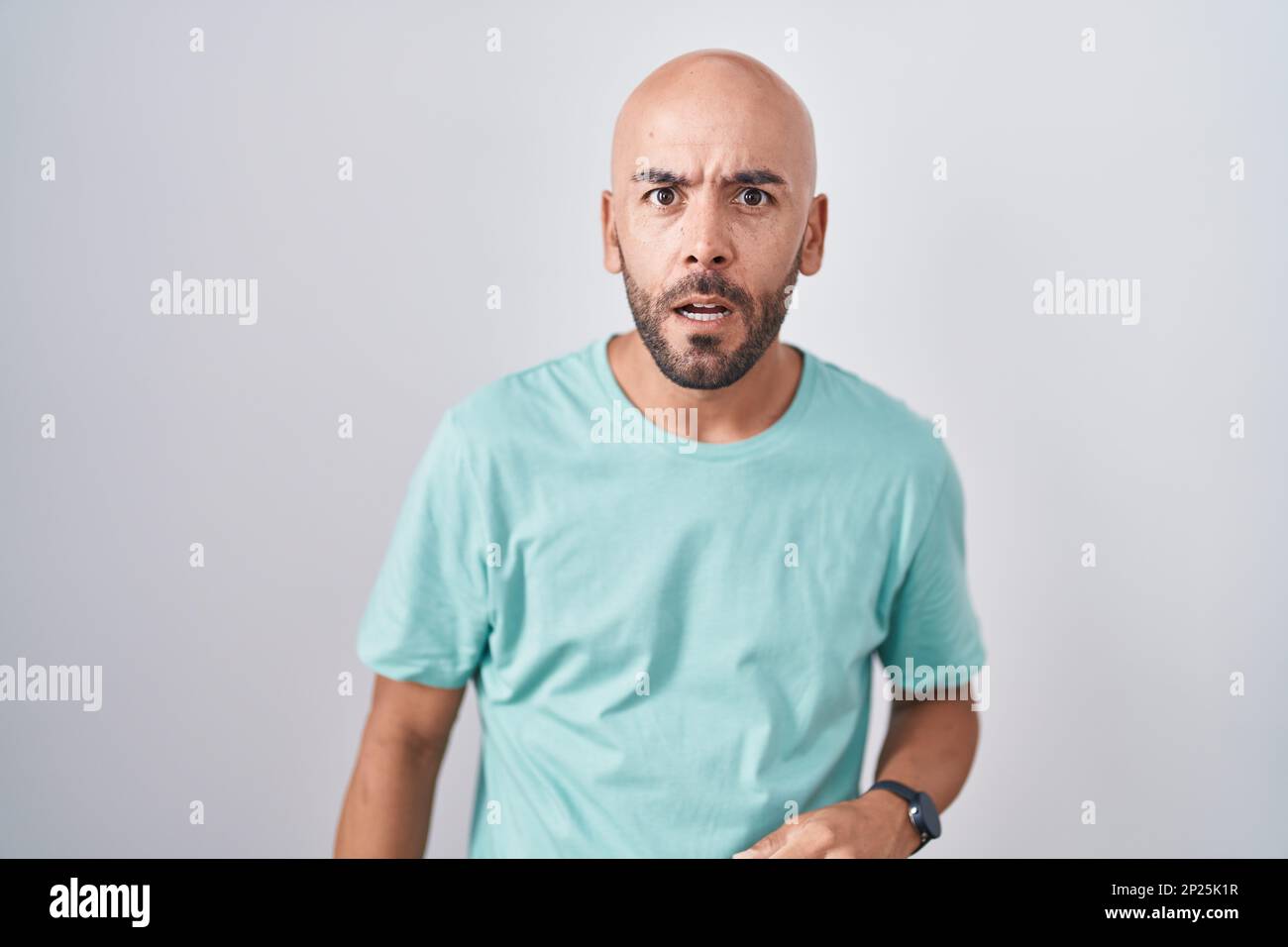 Middle age bald man standing over white background afraid and shocked ...