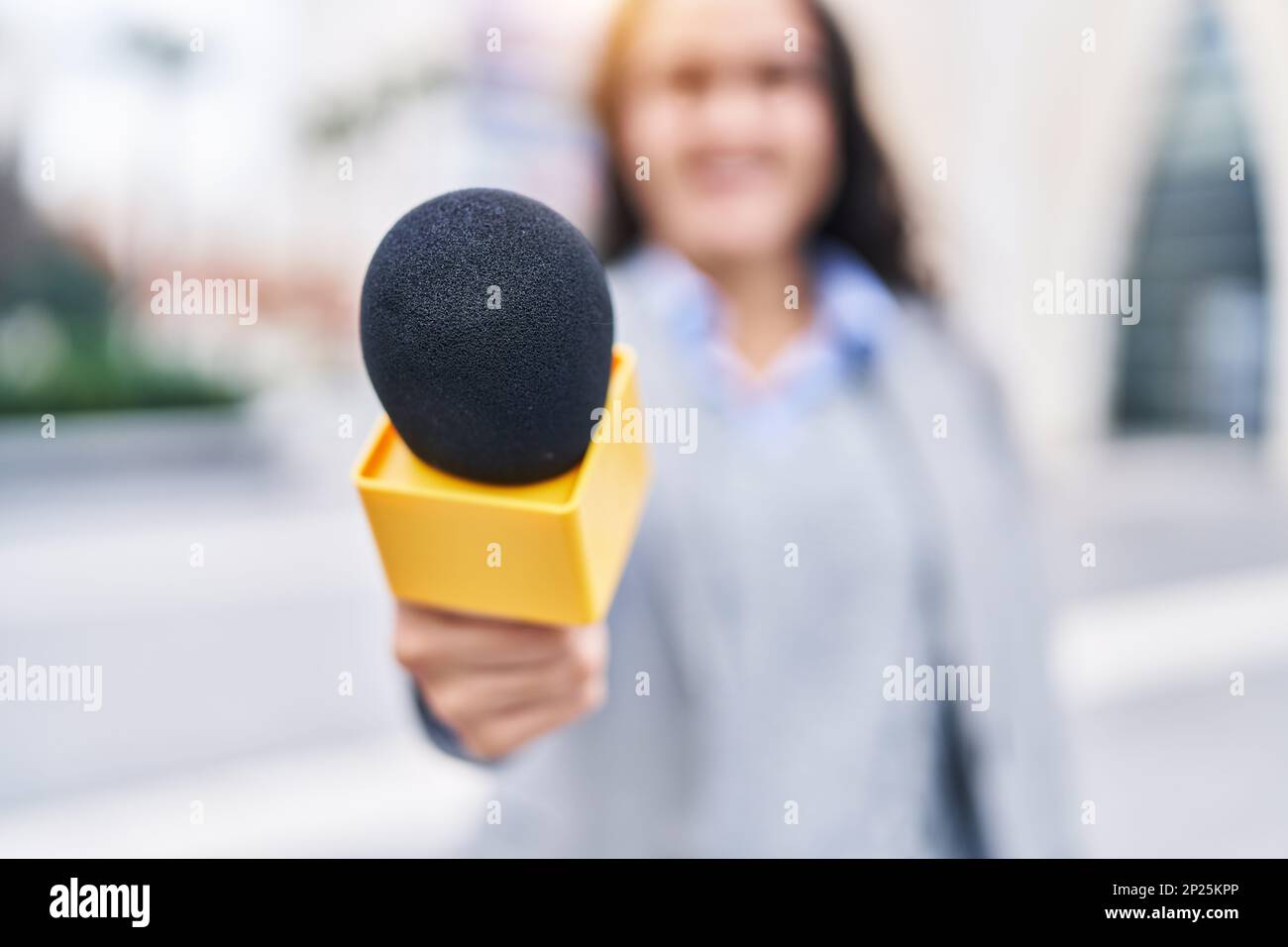 Young hispanic woman reporter working using microphone at street Stock ...