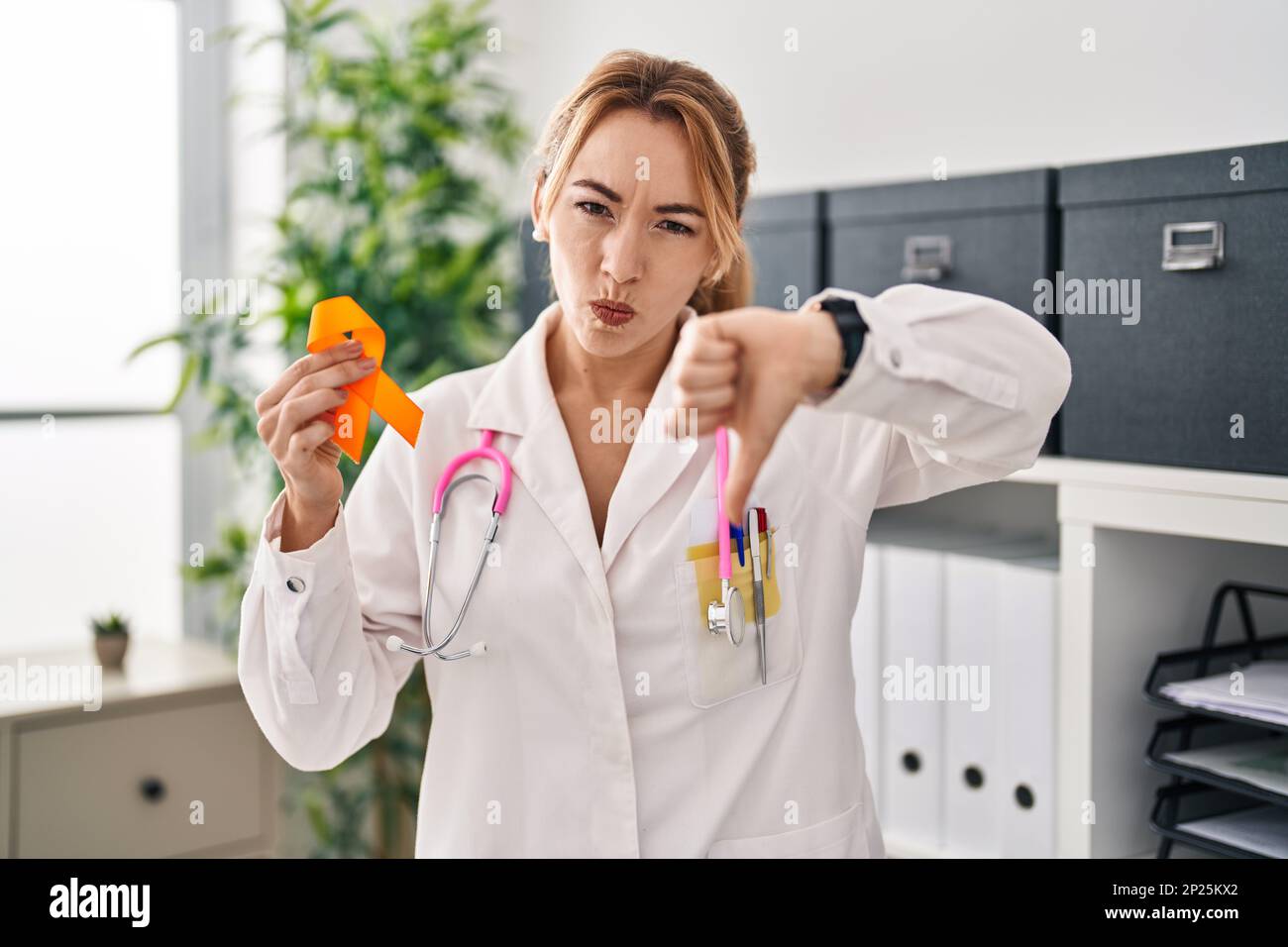 Hispanic doctor woman holding awareness orange ribbon with angry face ...