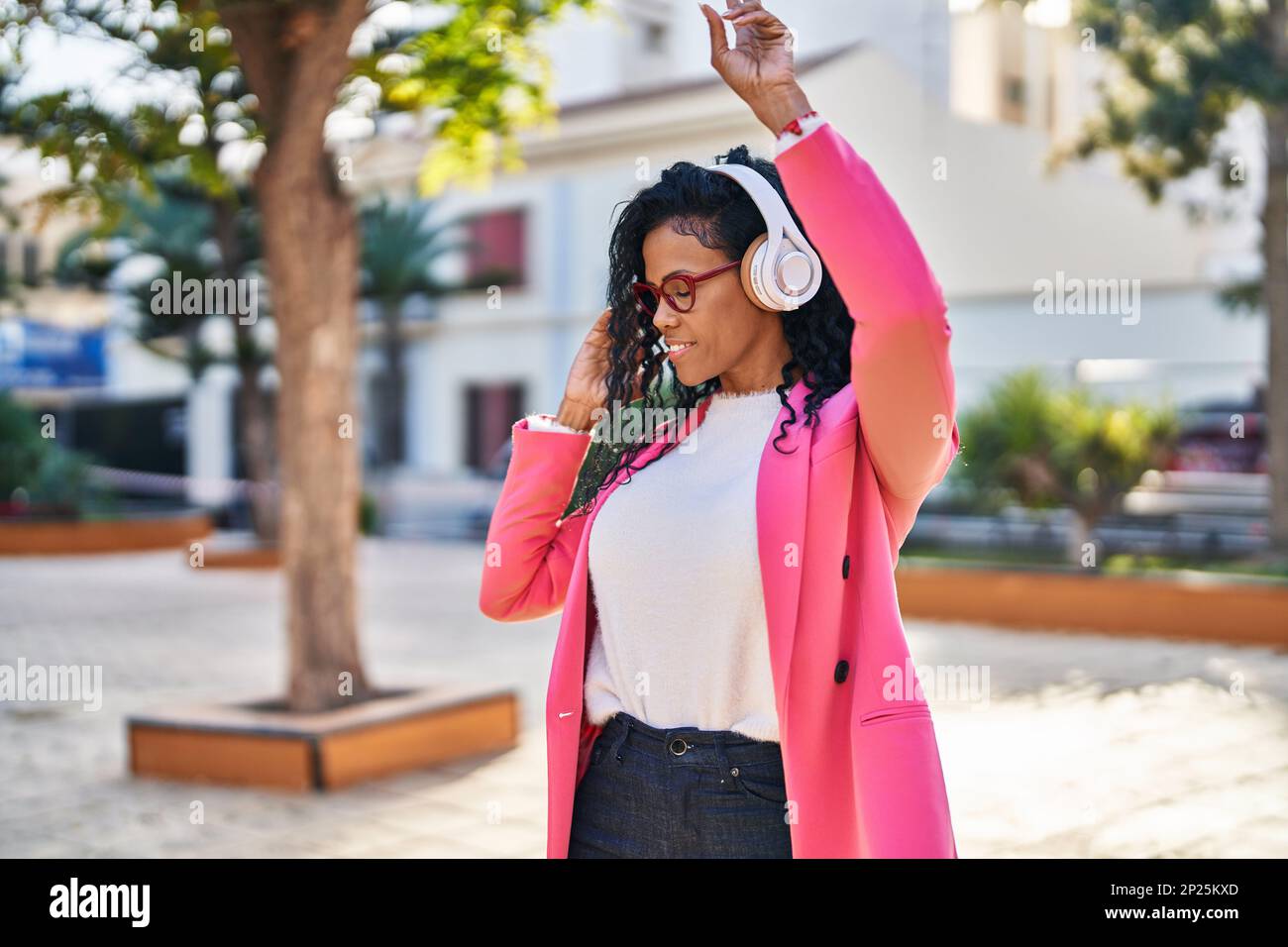 African american woman executive listening to music and dancing at park ...