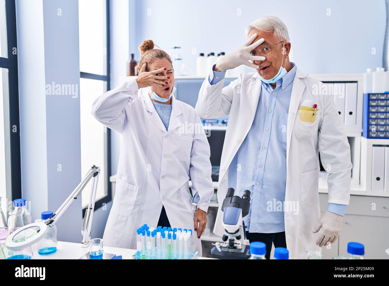 Middle age hispanic people working at scientist laboratory peeking in ...