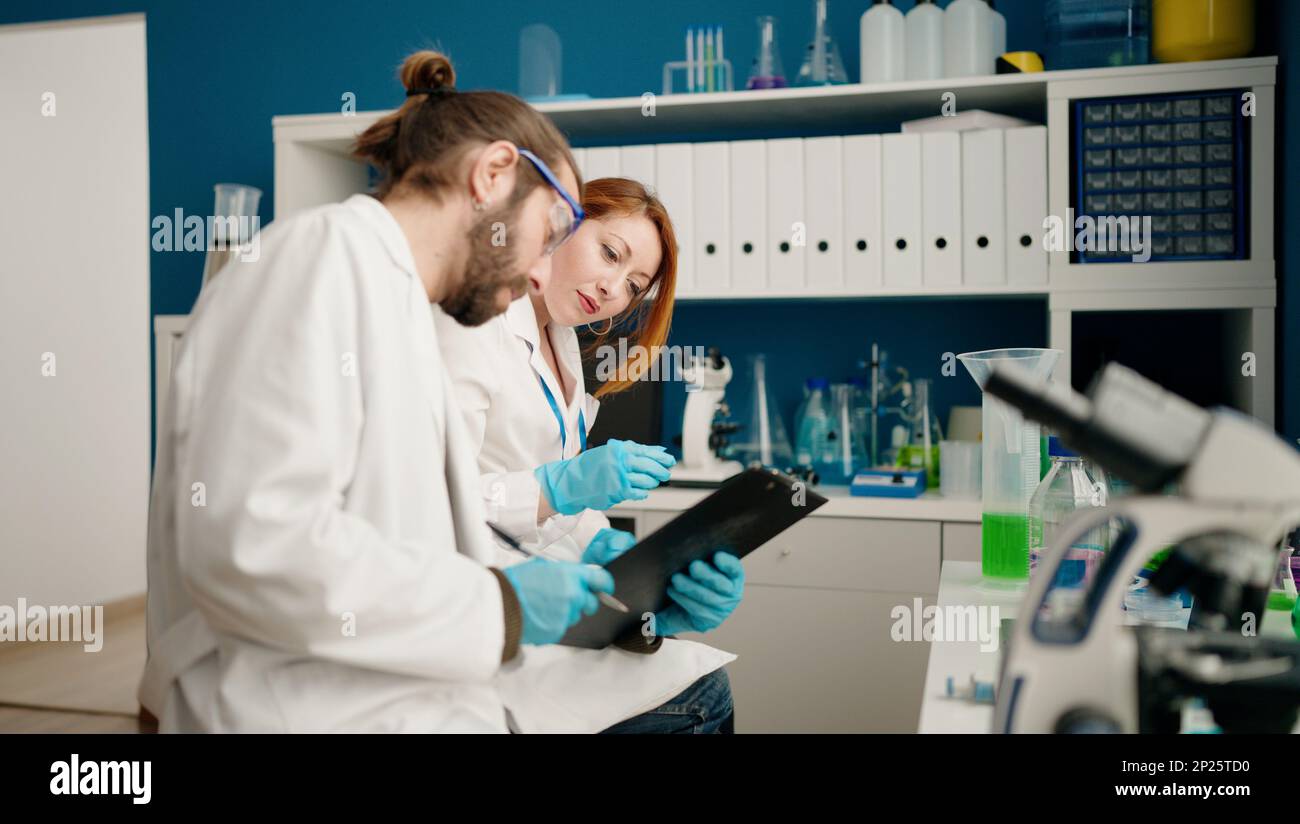 Man and woman wearing sciencist uniform writing on clipboard at ...