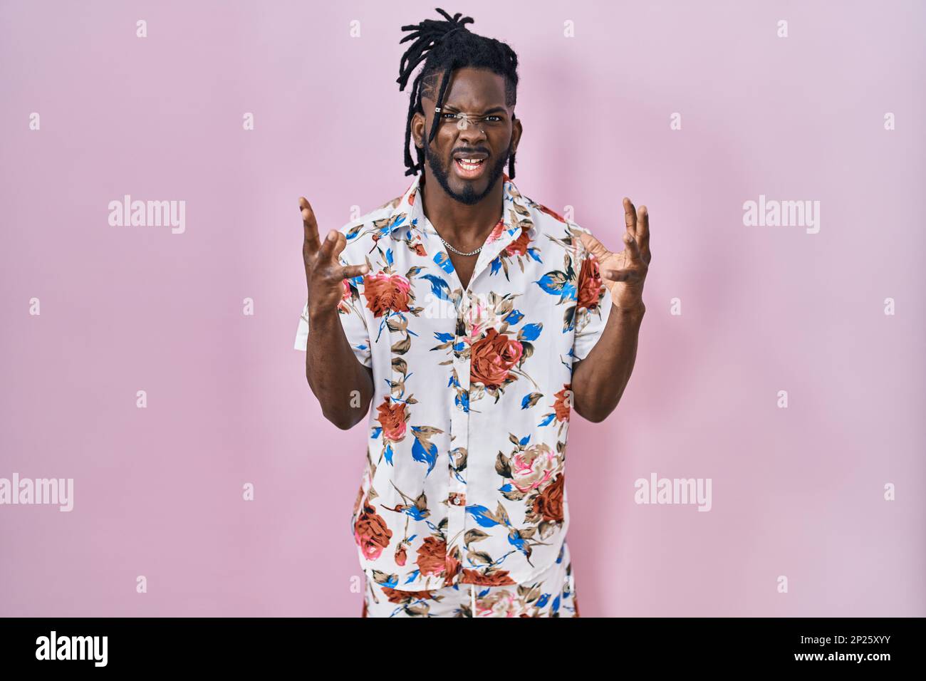 African man with dreadlocks wearing summer shirt over pink background ...