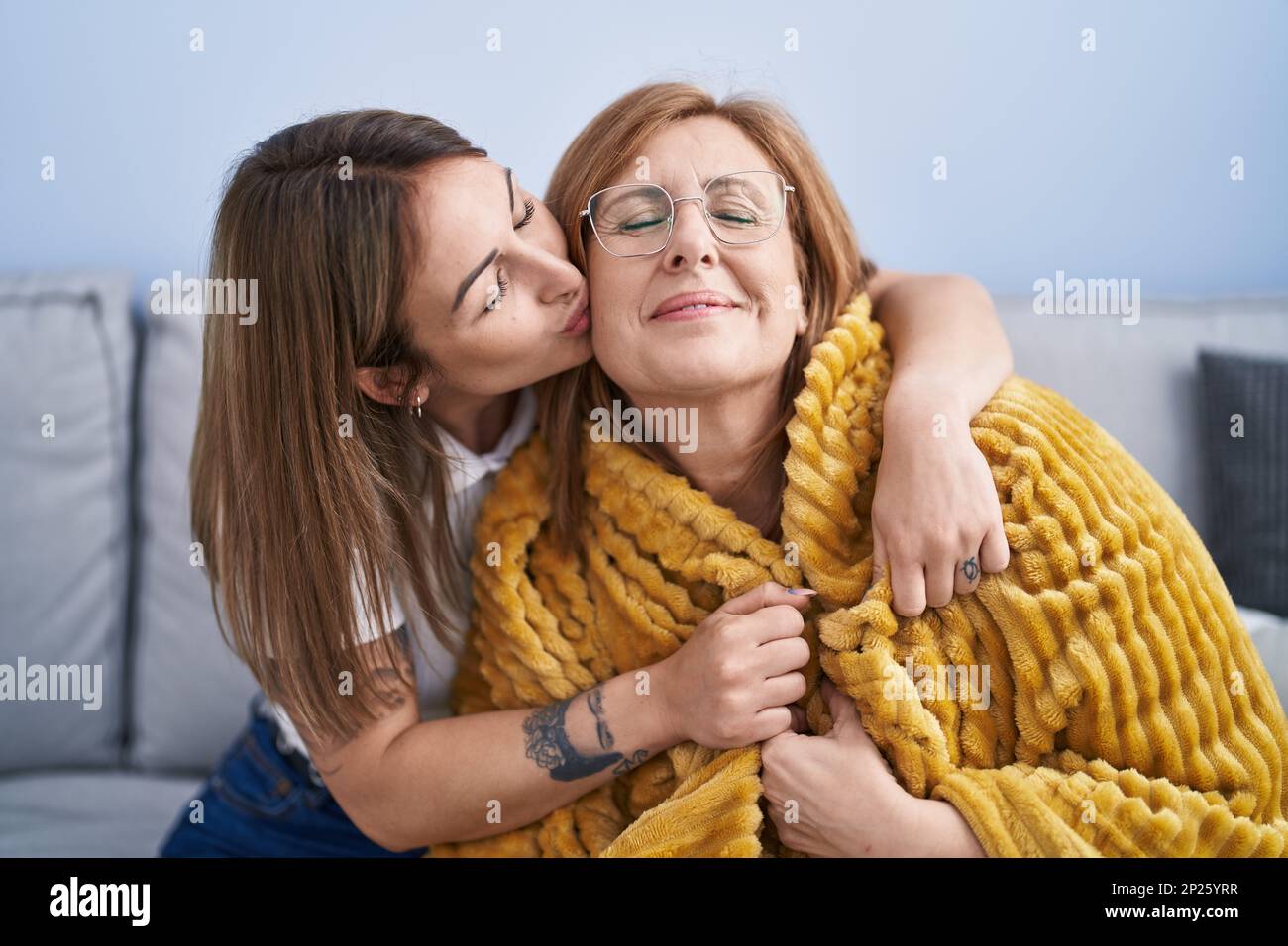 Mother and daughter hugging each other and kissing sitting on sofa at home Stock Photo - Alamy