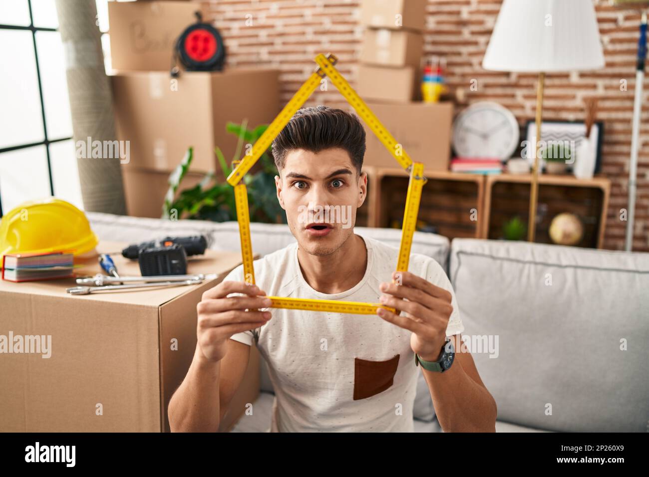 Young hispanic man moving to a new home in shock face, looking ...