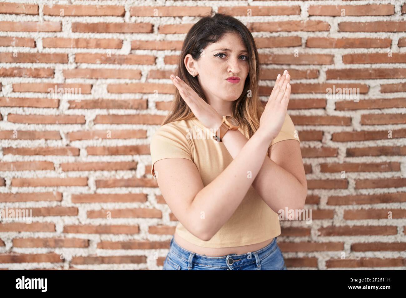 Young Brunette Woman Standing Over Bricks Wall Rejection Expression
