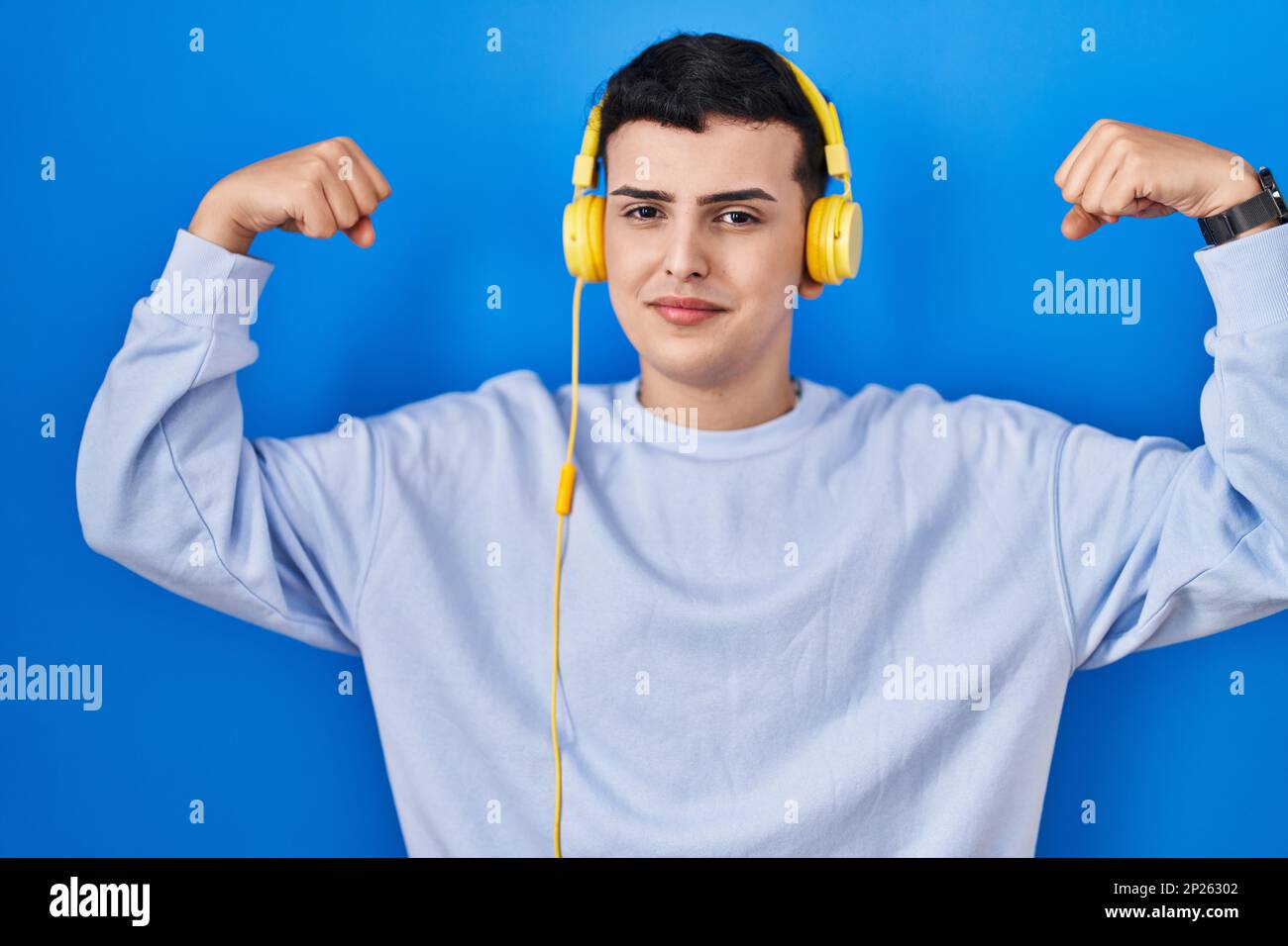 Non binary person listening to music using headphones showing arms ...