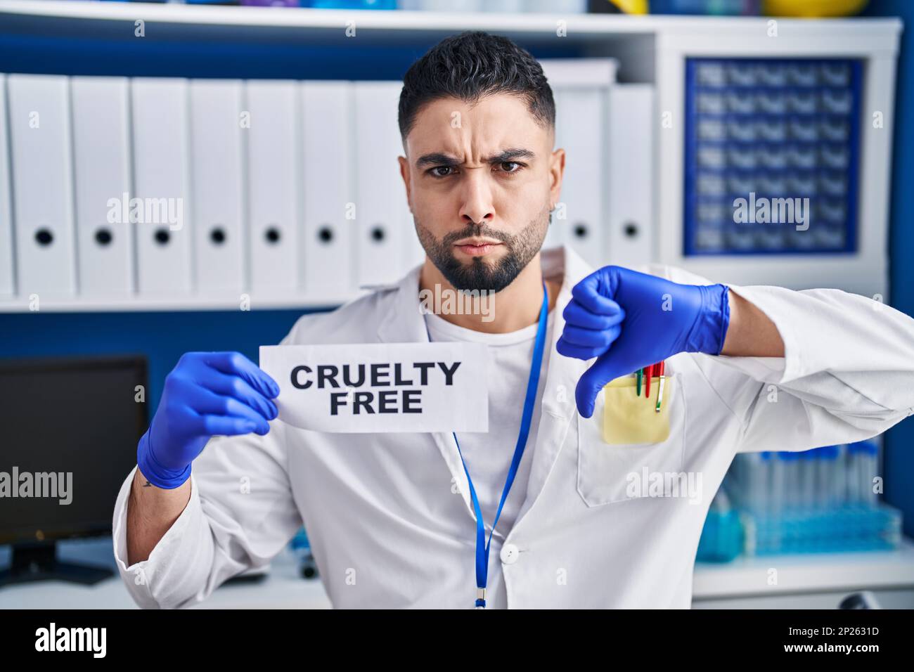 Young handsome man working at scientist laboratory holding cruelty free ...